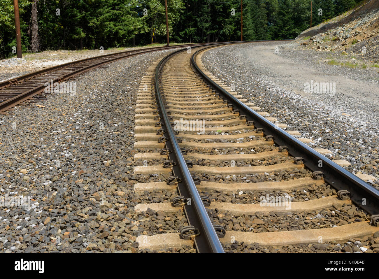 Two sets of train tracks curving around a hill Stock Photo - Alamy