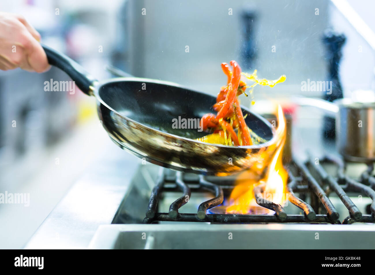 cooking in restaurant kitchen at the stove with pan Stock Photo - Alamy