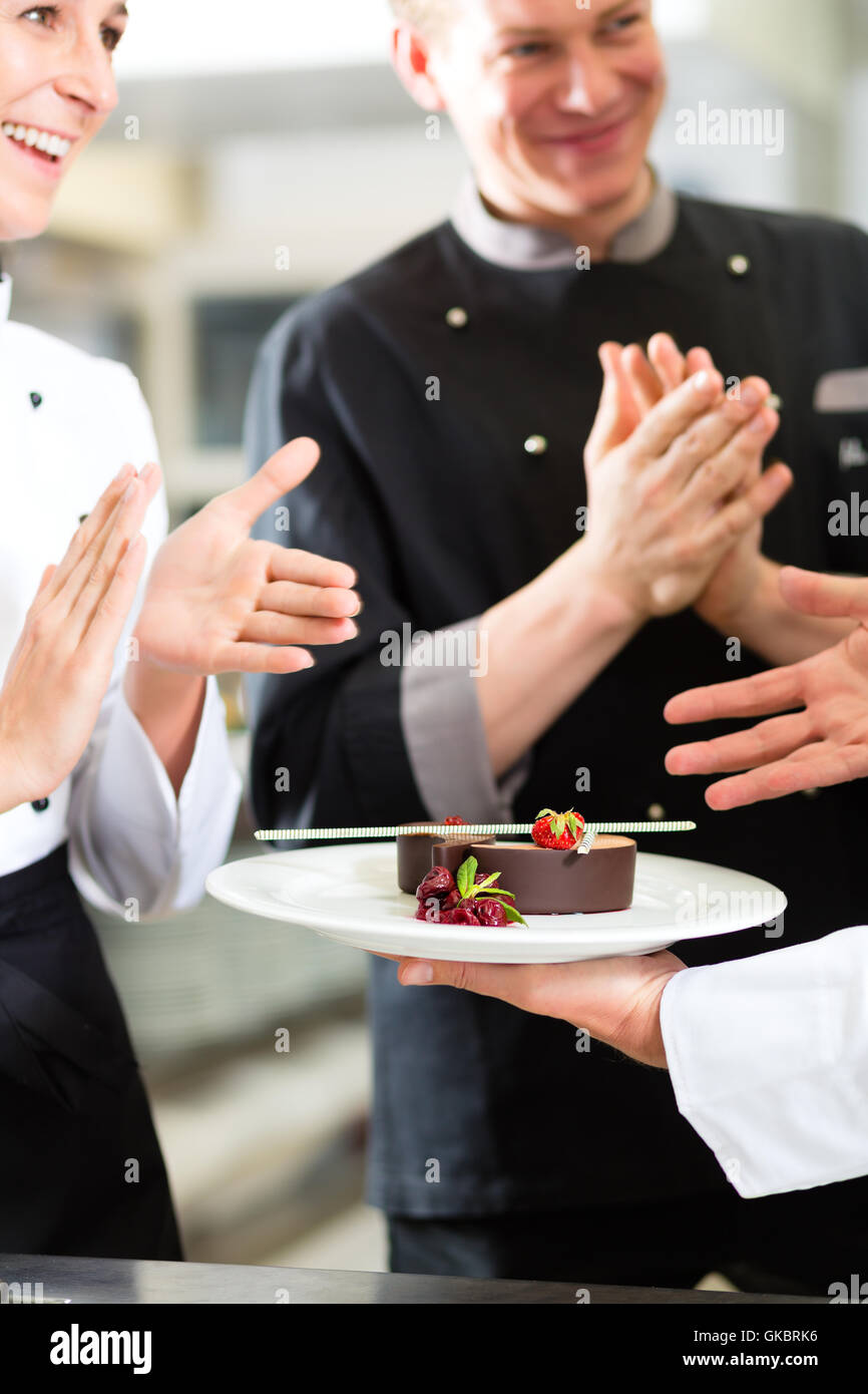 team of chefs with dessert in kitchen Stock Photo - Alamy