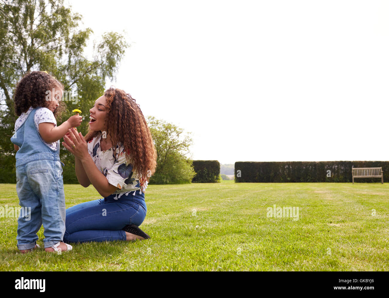 Young girl giving a flower to her mother, side view Stock Photo - Alamy