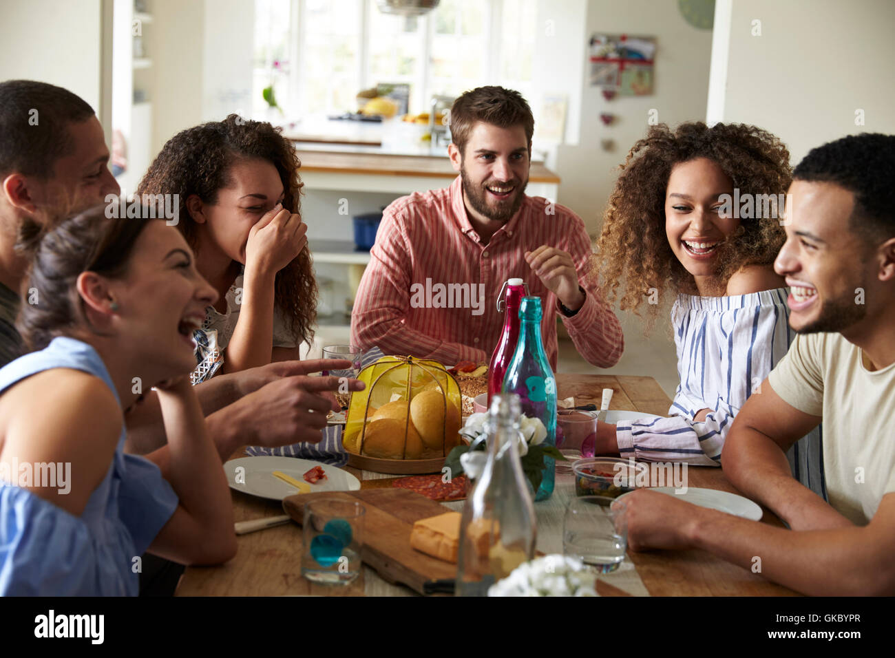 Young adults laughing as they talk at a table over lunch Stock Photo ...