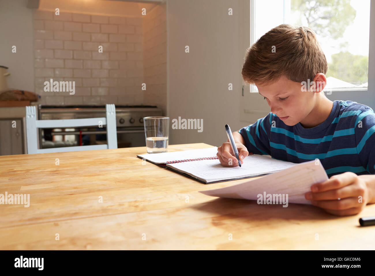 Boy Doing Homework Sitting At Kitchen Table Stock Photo - Alamy