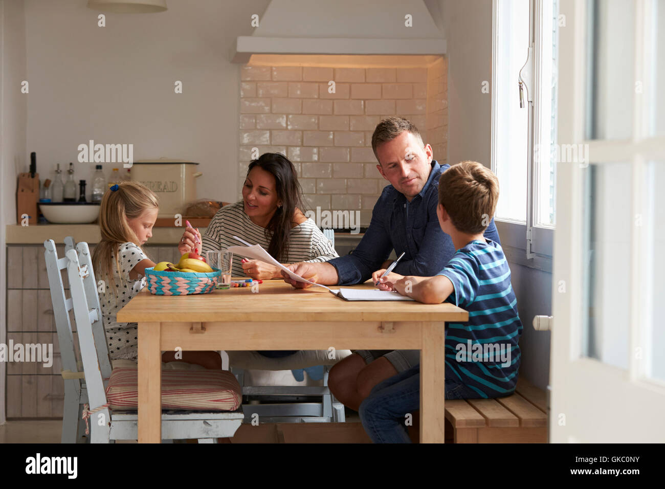Parents Helping Children With Homework At Kitchen Table Stock Photo - Alamy