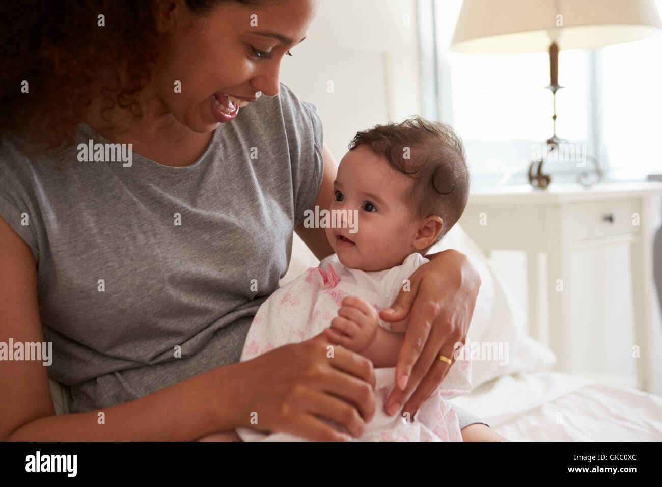 Mother Cuddling Baby Daughter In Bedroom At Home Stock Photo - Alamy