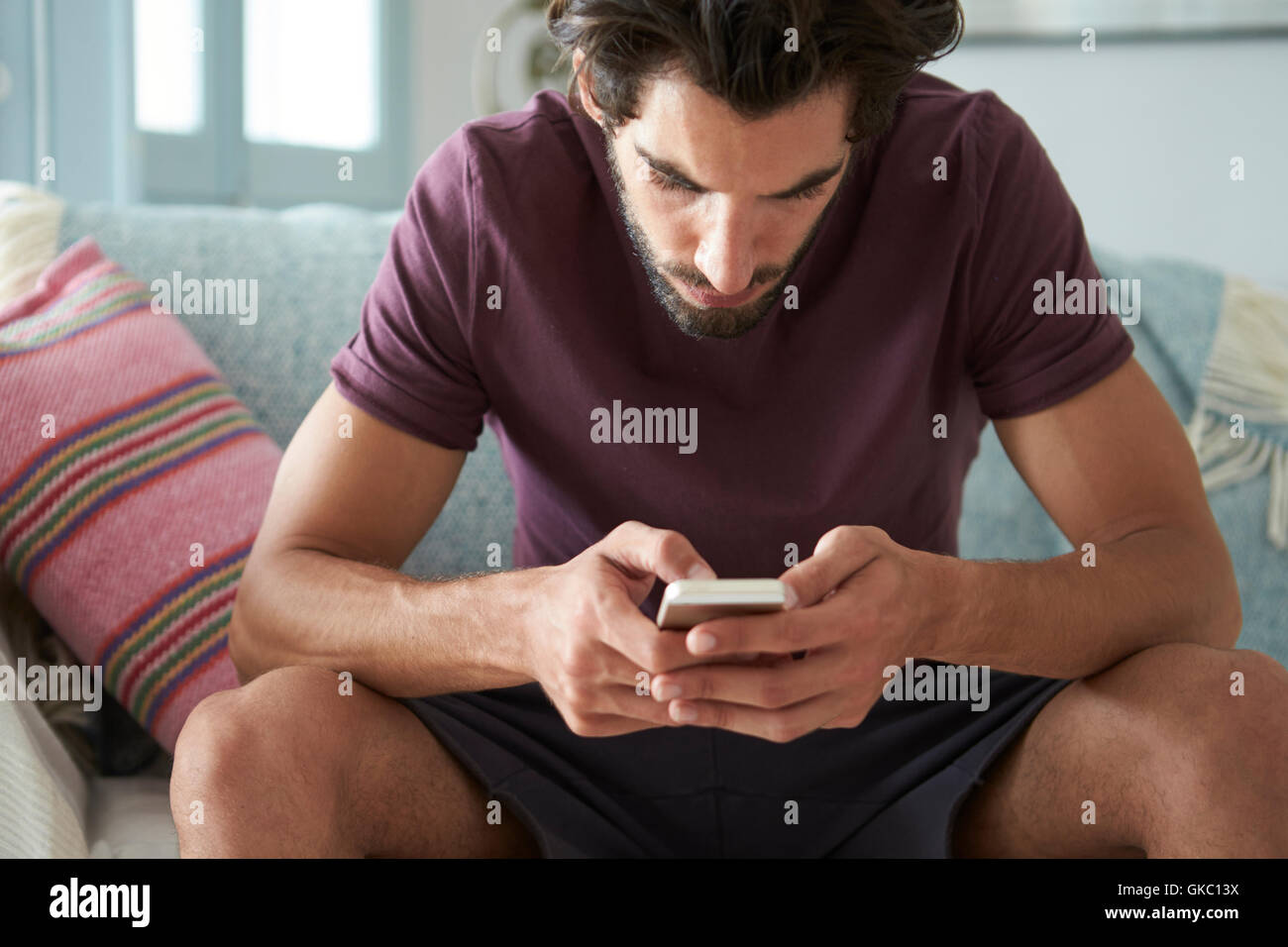 Man Sitting On Sofa Using Mobile Phone To Text Message Stock Photo - Alamy