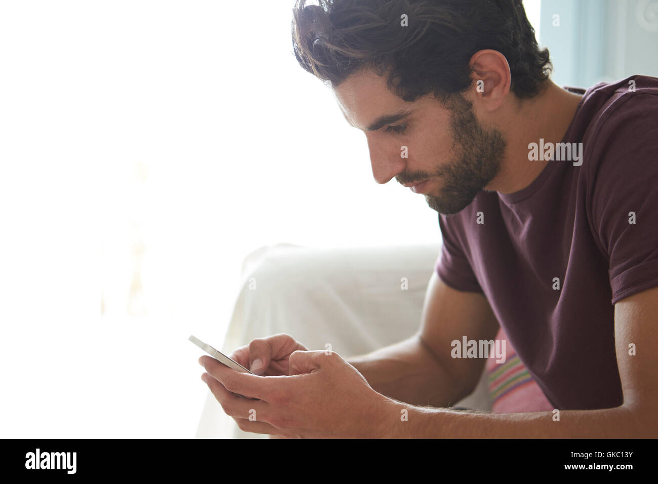 Man Sitting On Sofa Using Mobile Phone To Text Message Stock Photo - Alamy