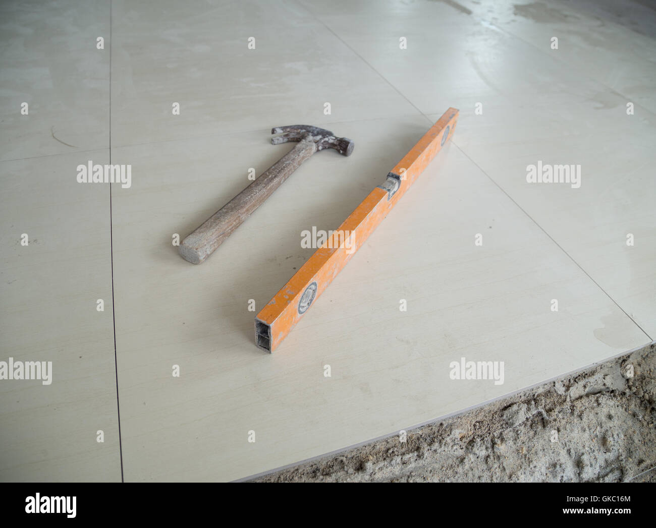 spirit level and hammer (tool for working tile) at construction site ...