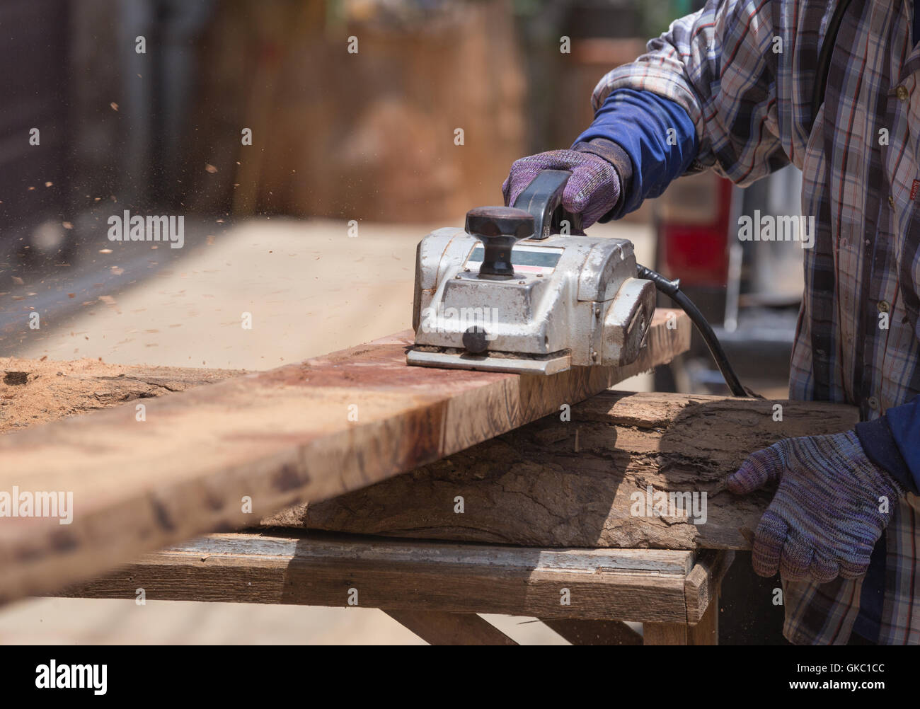 worker planing a plank of wood with a electric plane Stock Photo - Alamy