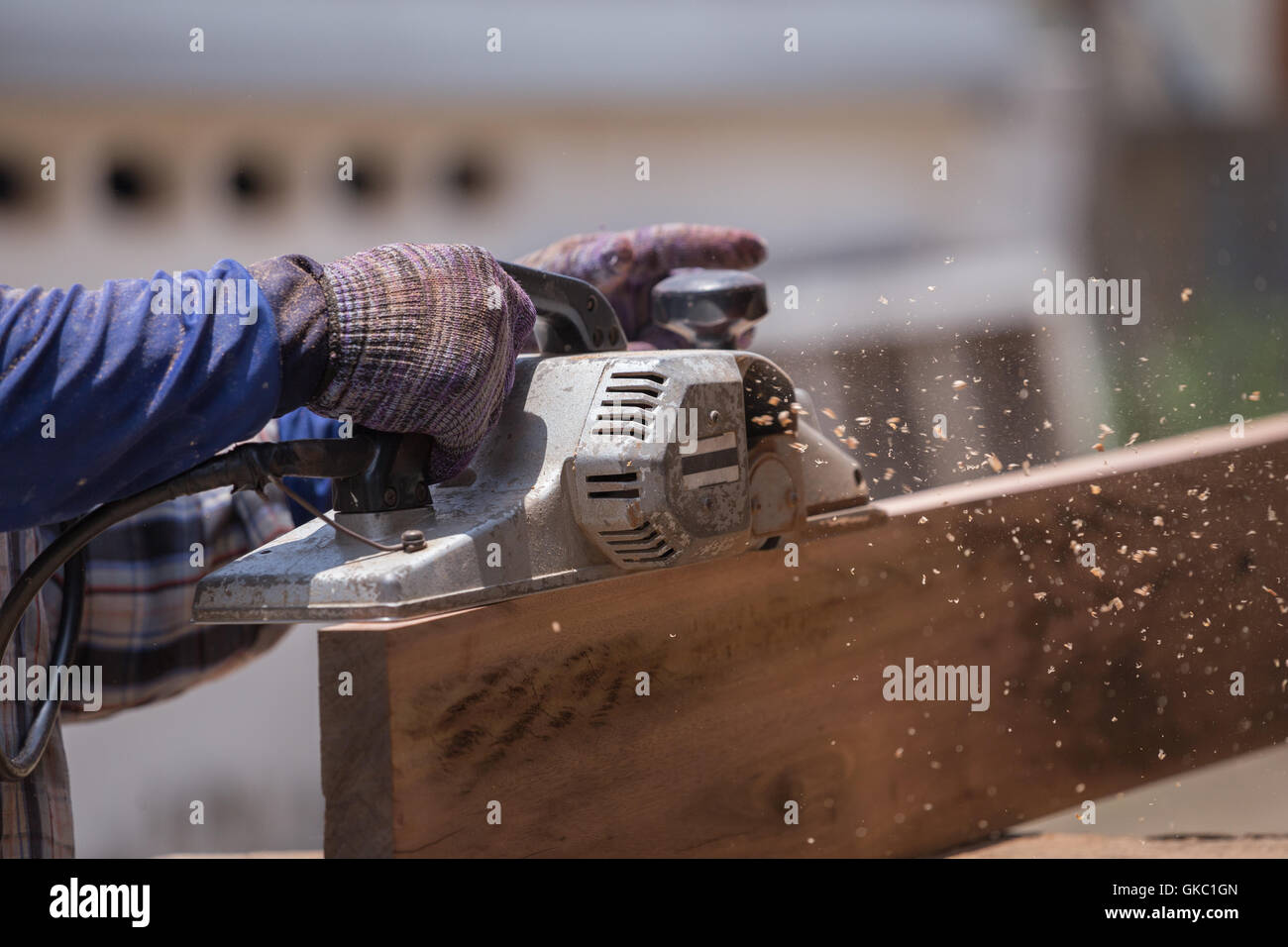 worker planing a plank of wood with a electric plane Stock Photo - Alamy