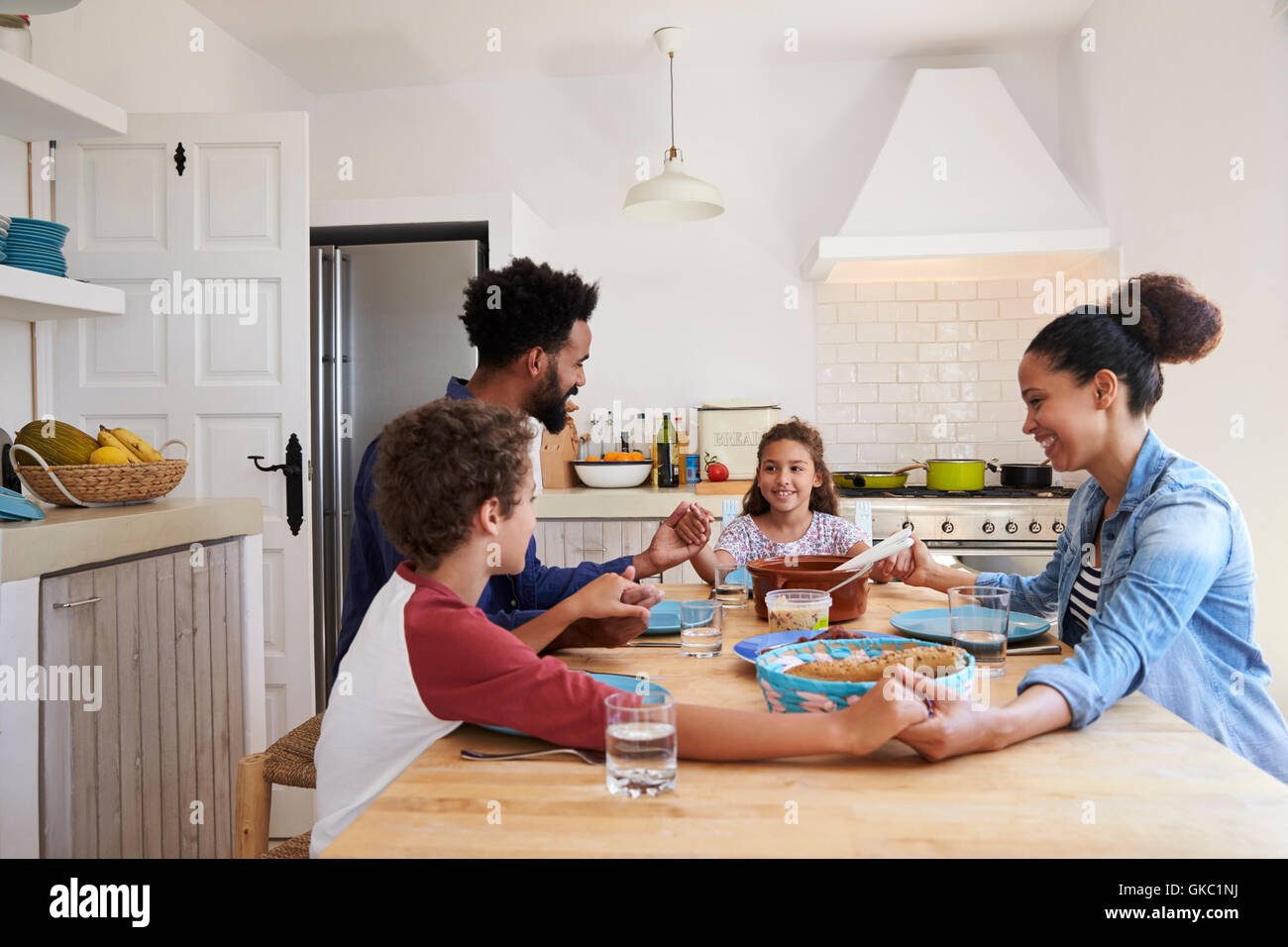 Family hold hands around the kitchen table before their meal Stock ...