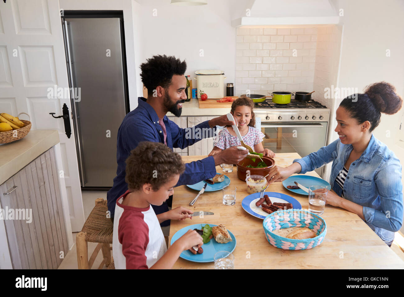 Happy family eating together at their kitchen table Stock Photo - Alamy