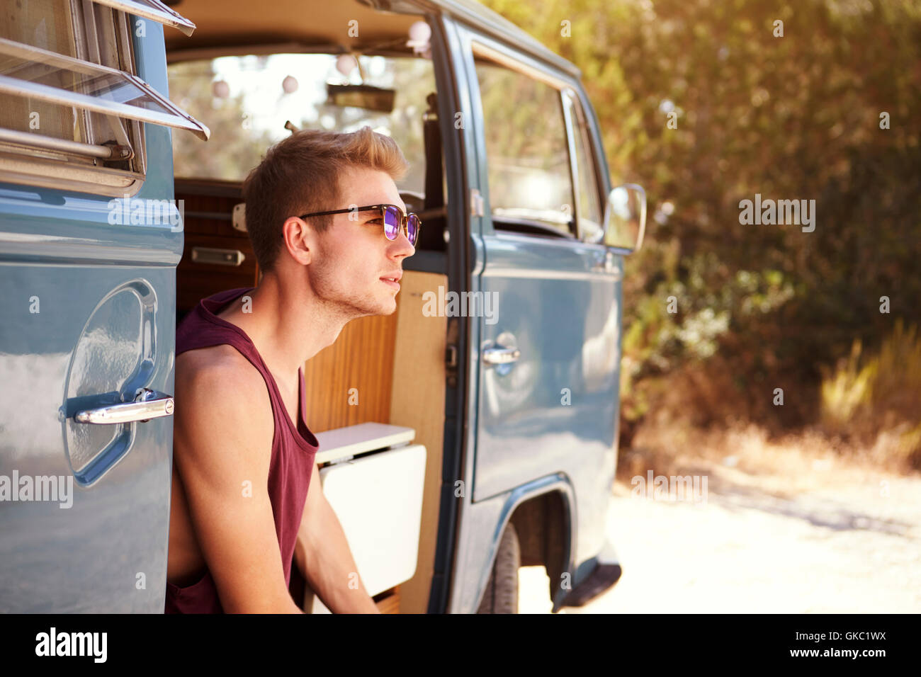 Young man sitting in the open doorway of a camper van Stock Photo - Alamy
