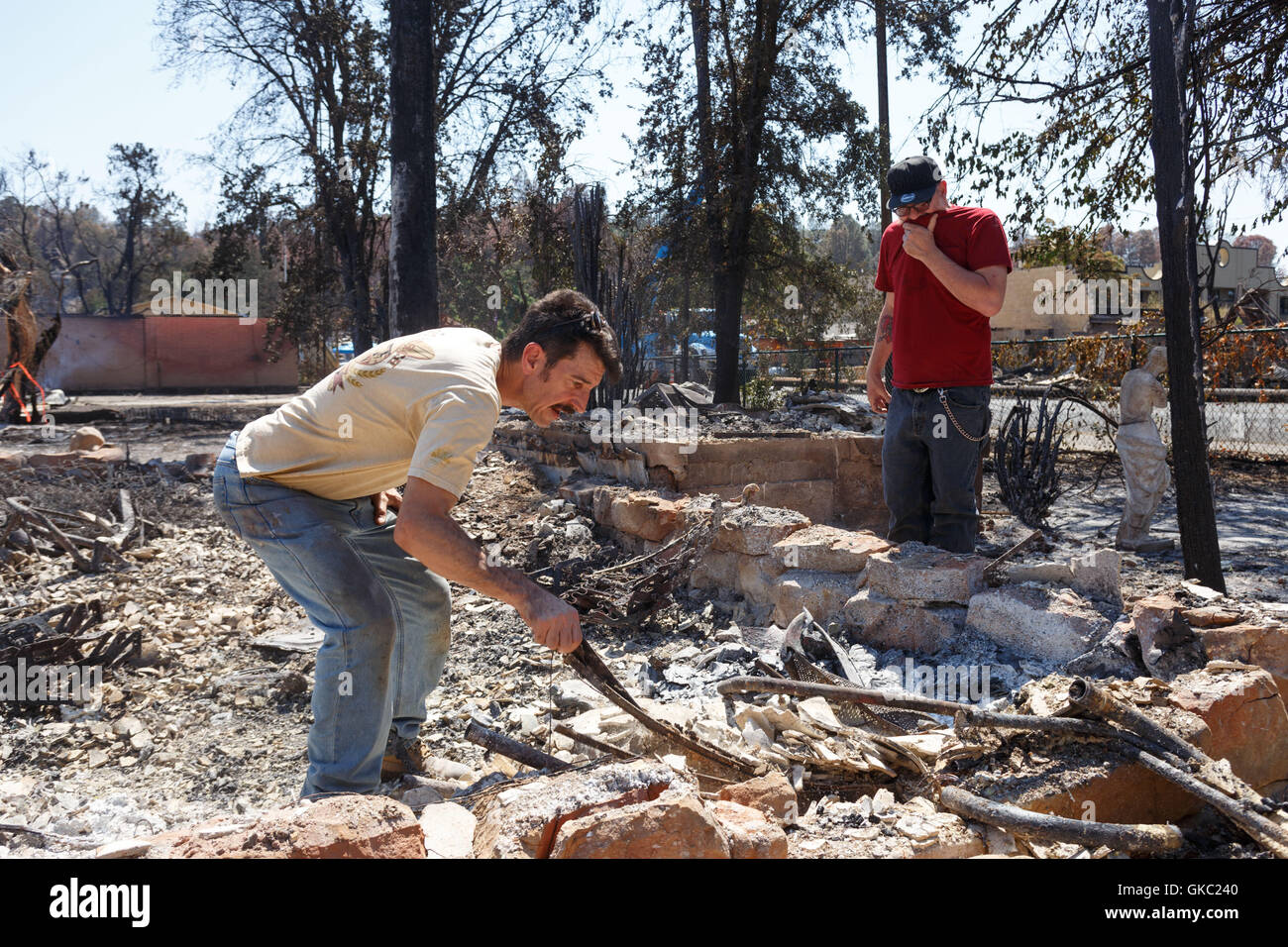 Rick Barger stands by as his friend Duane Barbic examines the remains of his house, which burned ...