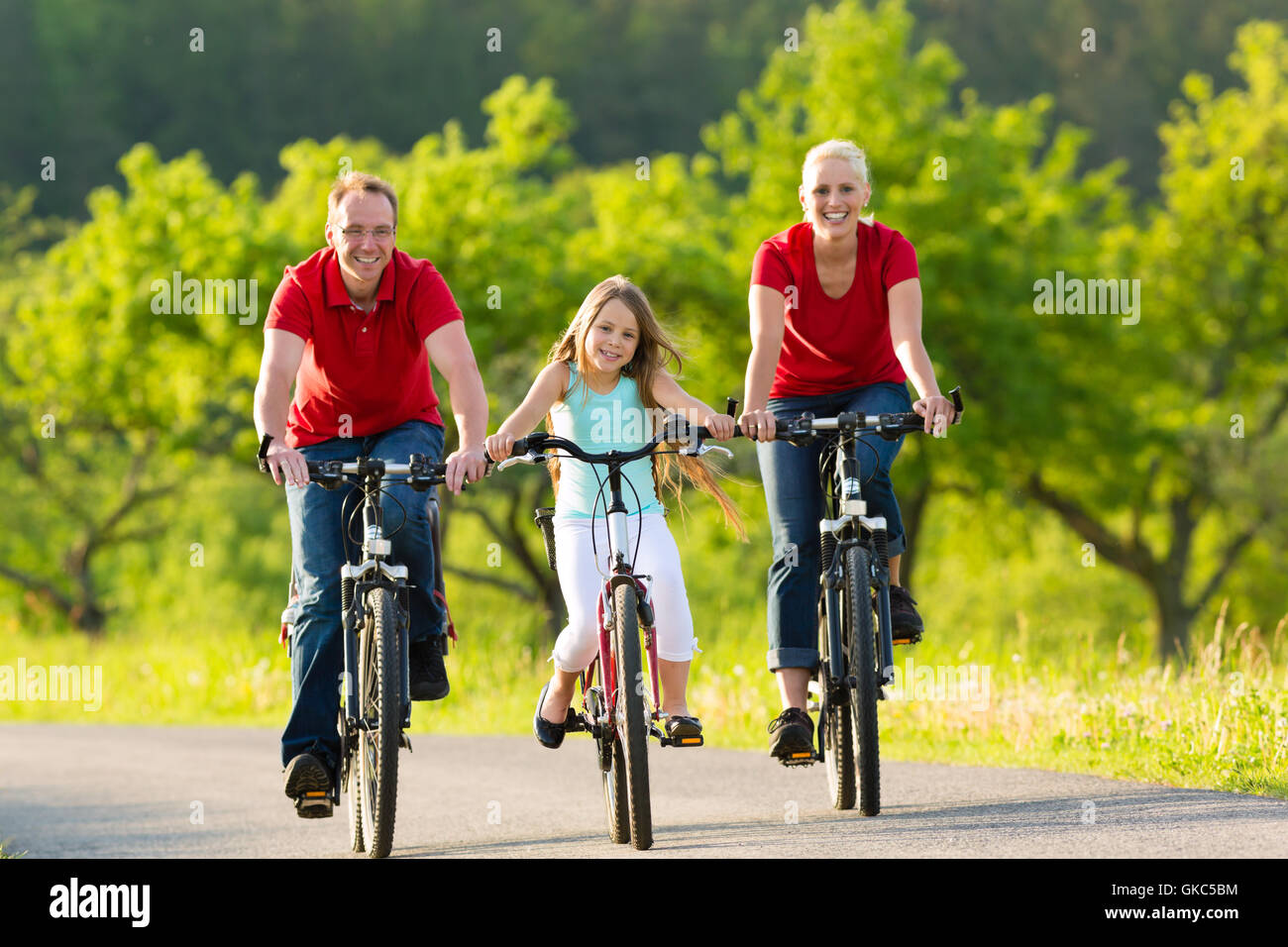 family rides a bike in the summer Stock Photo - Alamy