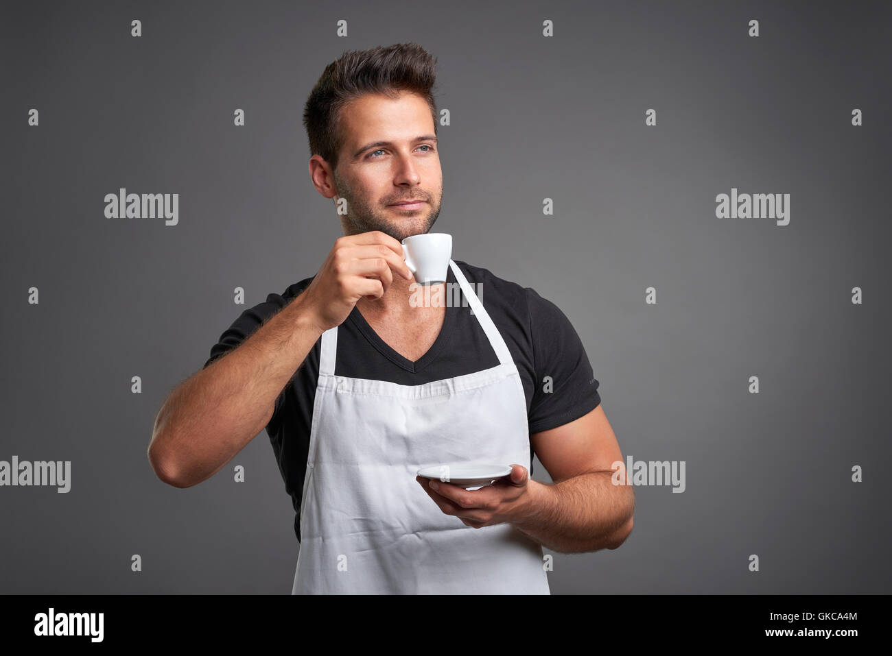 A young barista man smiling and enjoying a cup of coffee Stock Photo ...