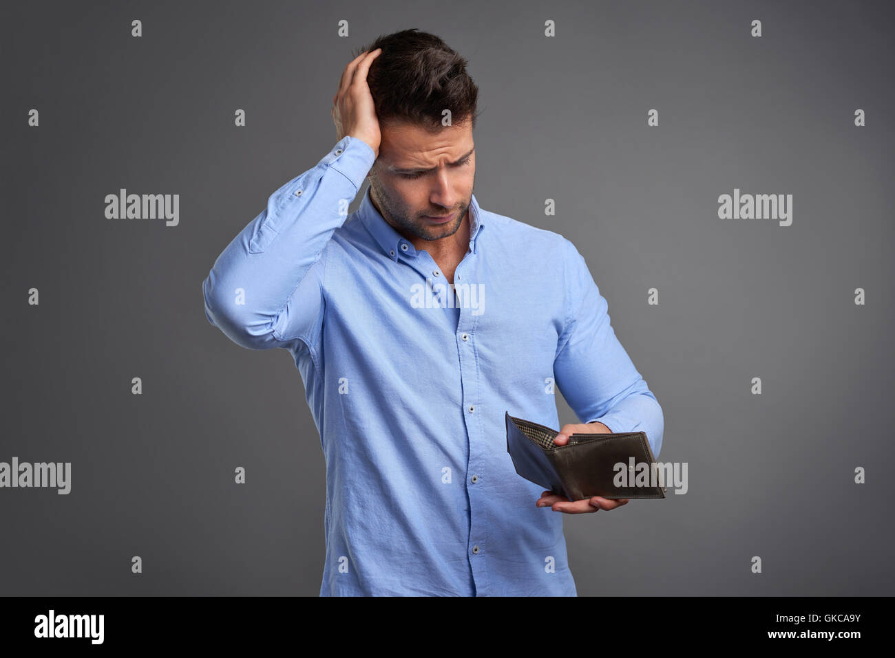 A poor handsome young man feeling stressed while looking at his empty ...