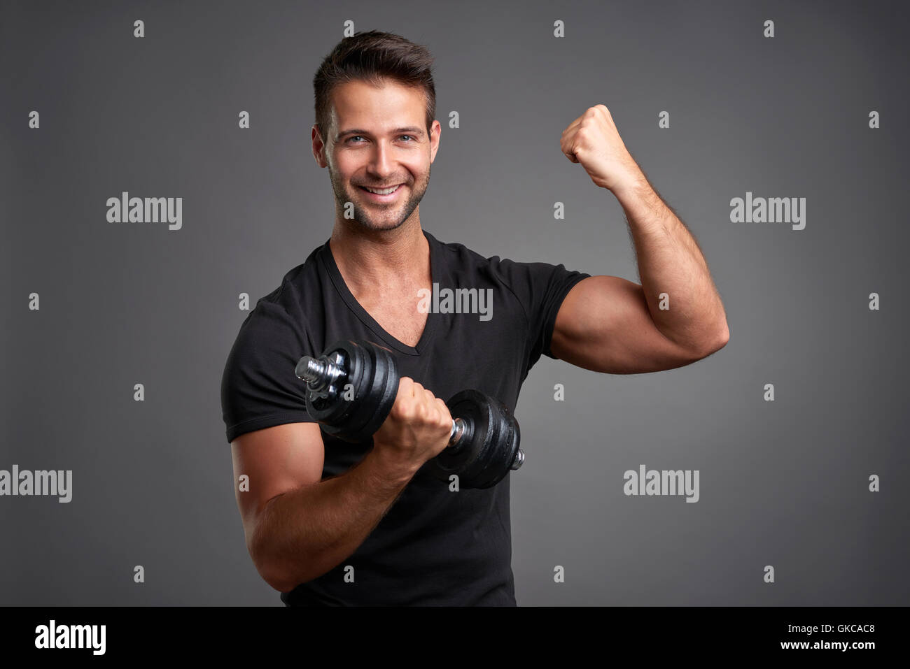 A handsome young man lifting weight smiling and raising his fist Stock ...