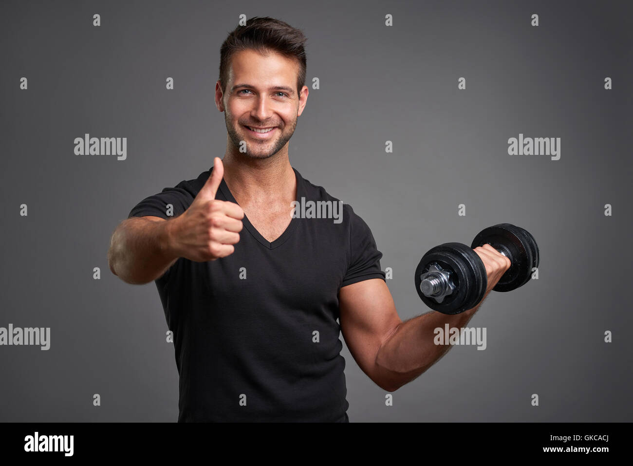 A handsome young man lifting weight smiling and showing thumbs up Stock ...