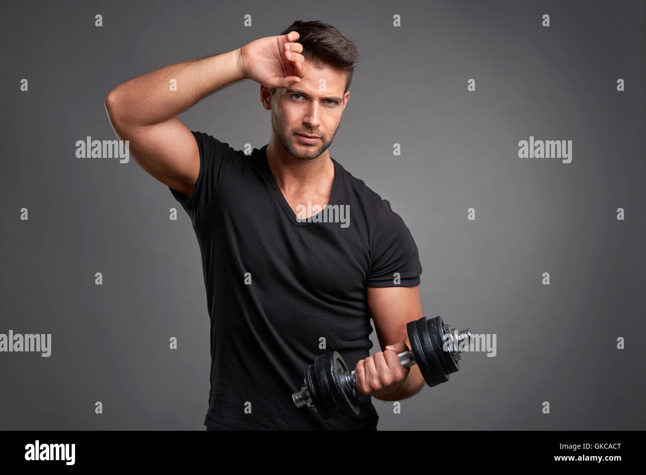 A handsome young man lifting weight and feeling tired Stock Photo - Alamy