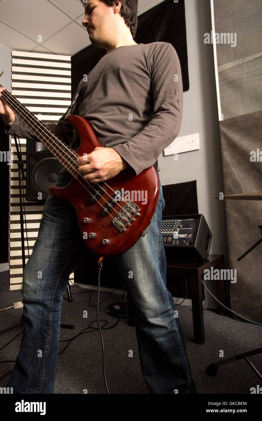 A Rock musician playing passionately bass in the rehearsal Studio Stock ...