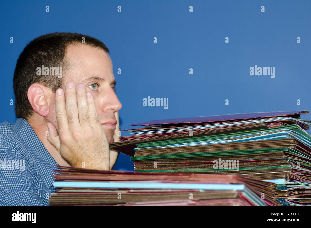 Man with head in hand looking out dreaming of the weekend while work is ...