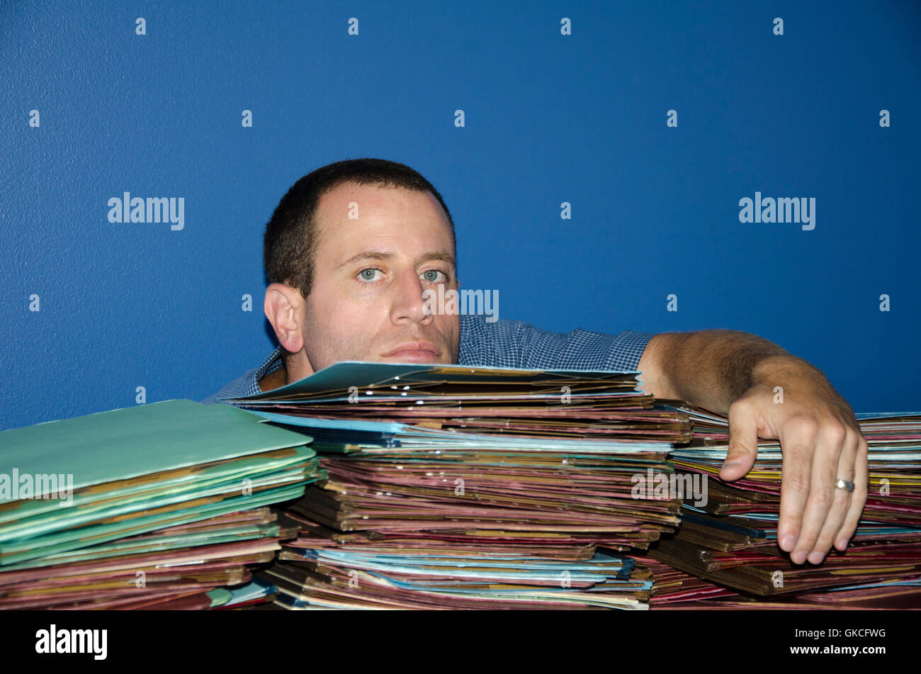 Man with piles of files in front of him bored at work Stock Photo - Alamy