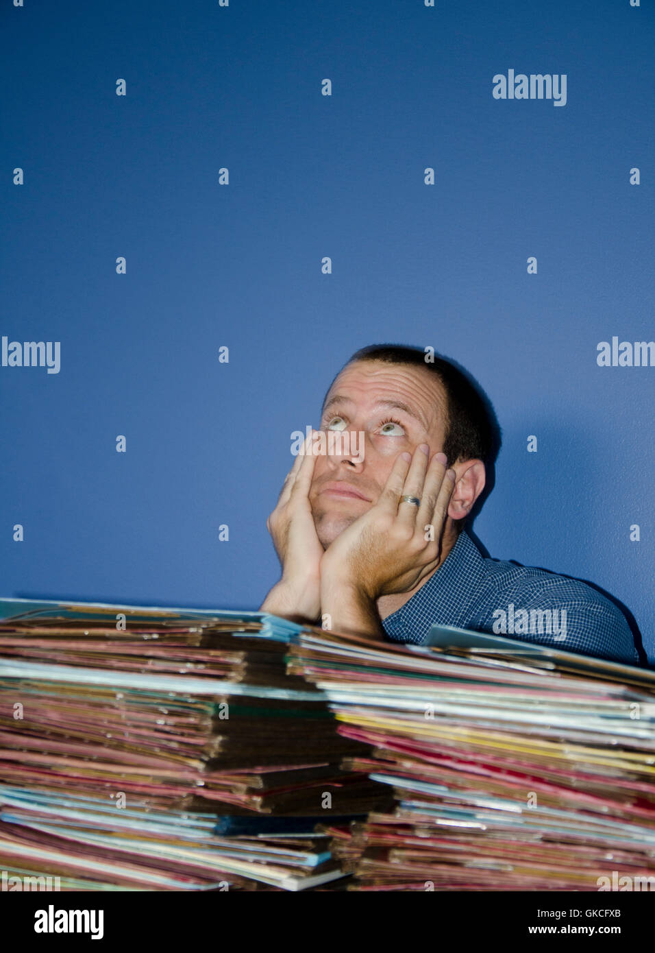 Man hiding behind piles files looking up at the ceiling. Example of an ...