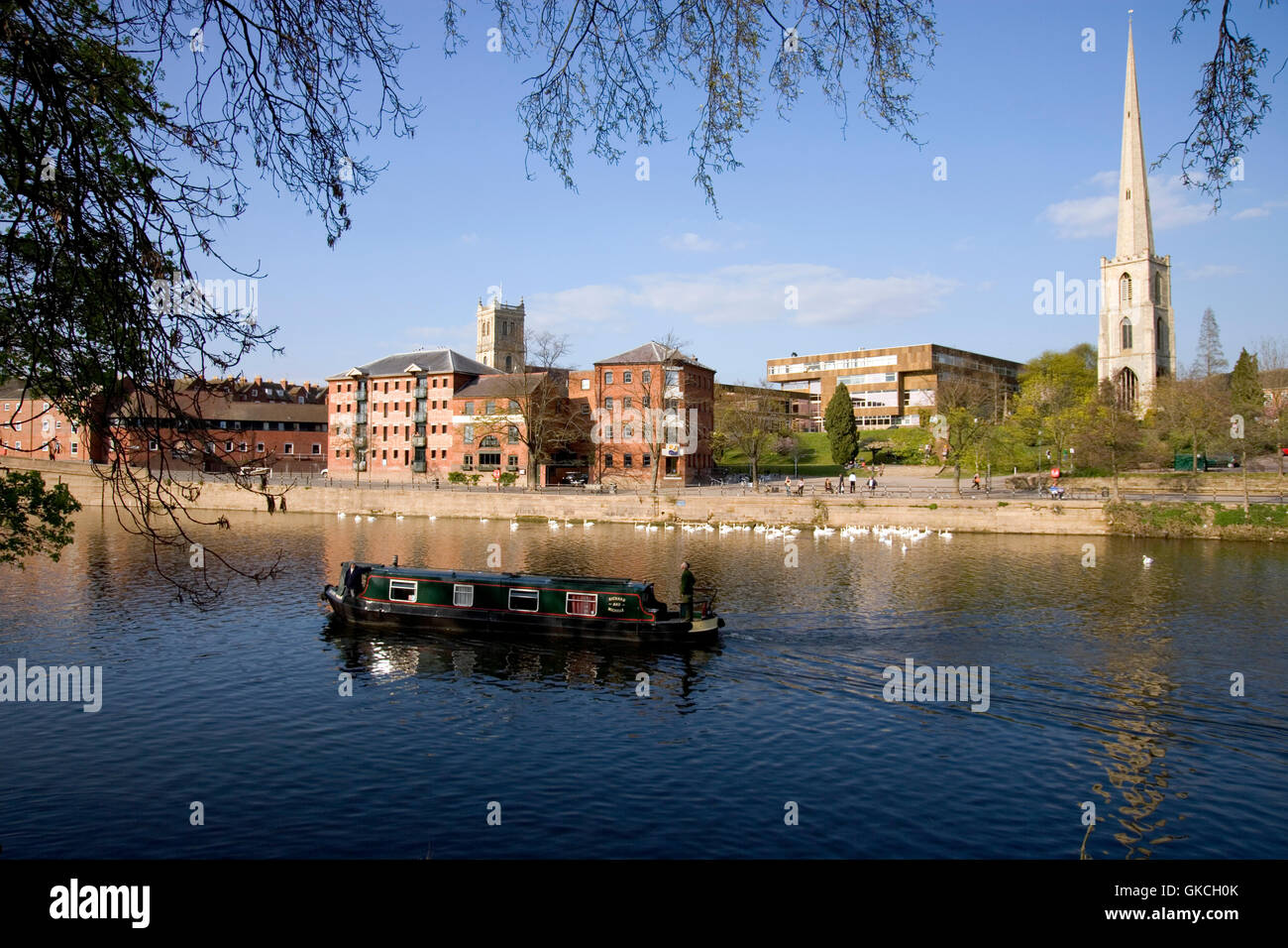 A canal boat passing restored industrial buildings on the riverside ...