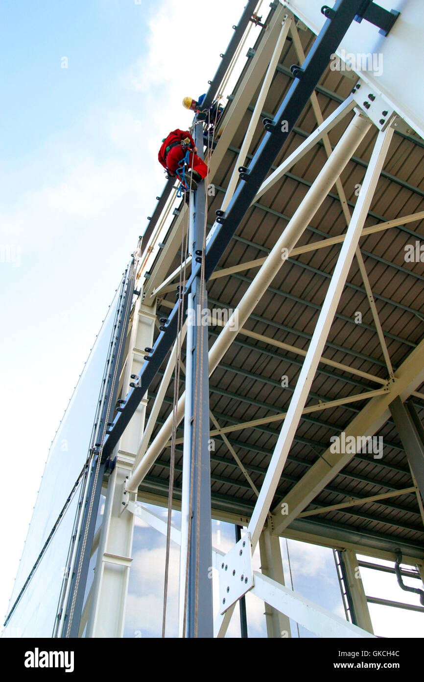 Abseilers installing fabric screens on an industrial building Stock ...