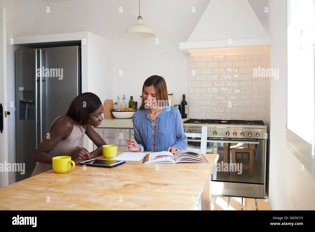Two friends researching recipes at the kitchen table Stock Photo - Alamy