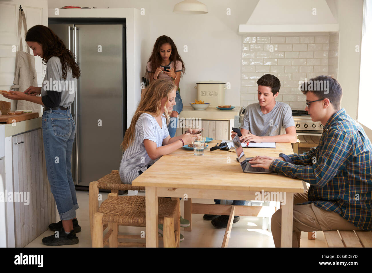 Teenage friends in kitchen, doing homework and making food Stock Photo ...
