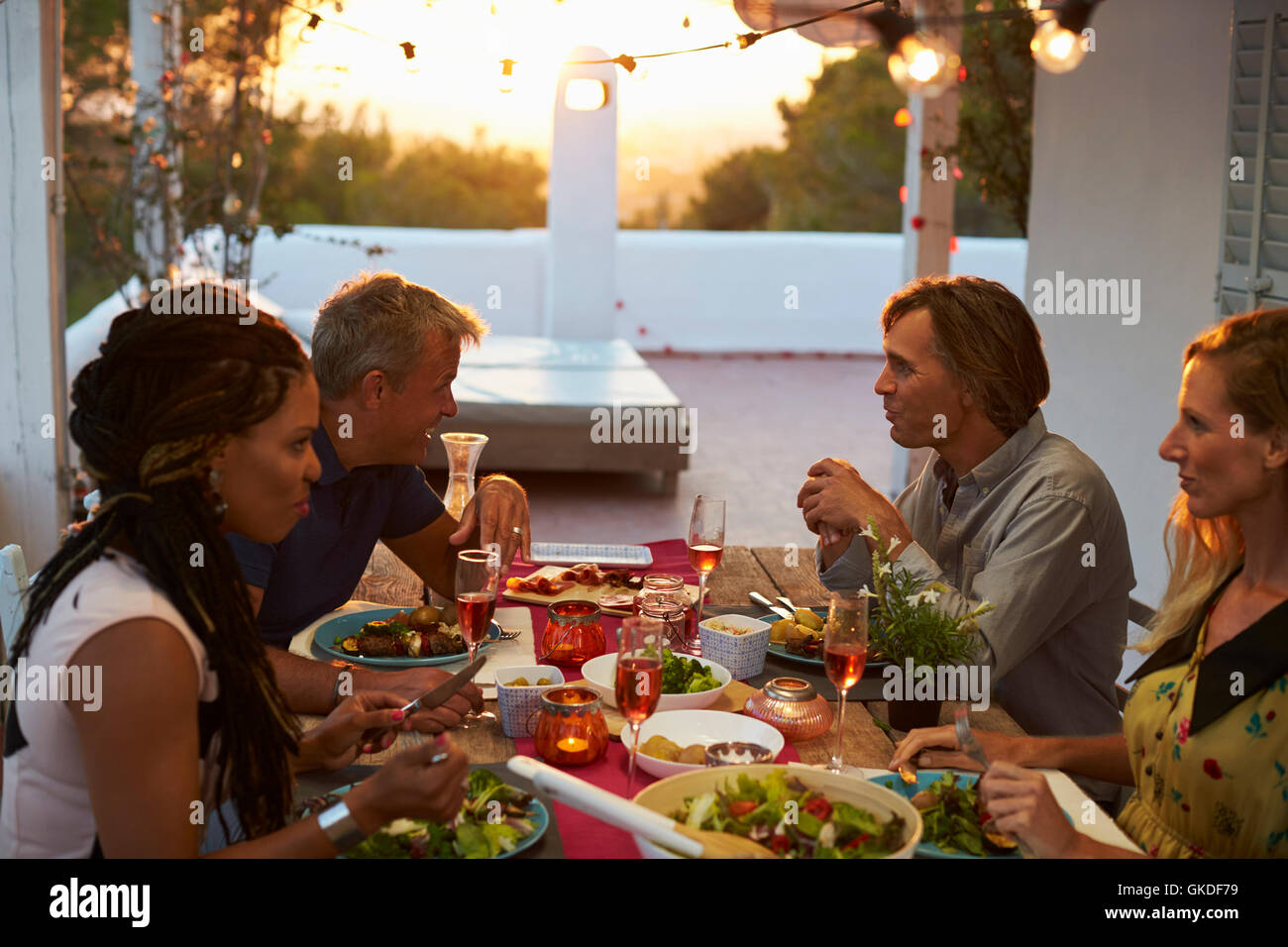 Two couples eating dinner on a roof terrace, close up Stock Photo - Alamy