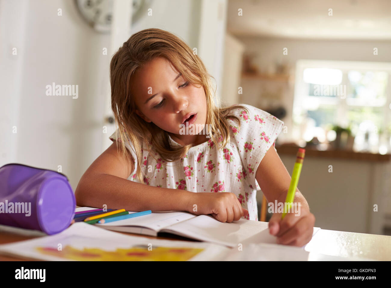 Girl concentrating on writing her homework Stock Photo - Alamy