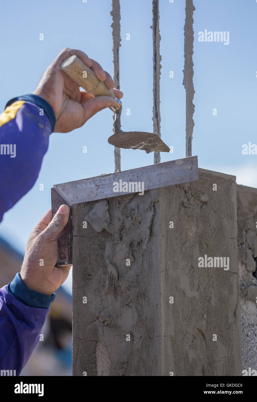 worker use iron ruler snd trowel plastering the poles at construction ...