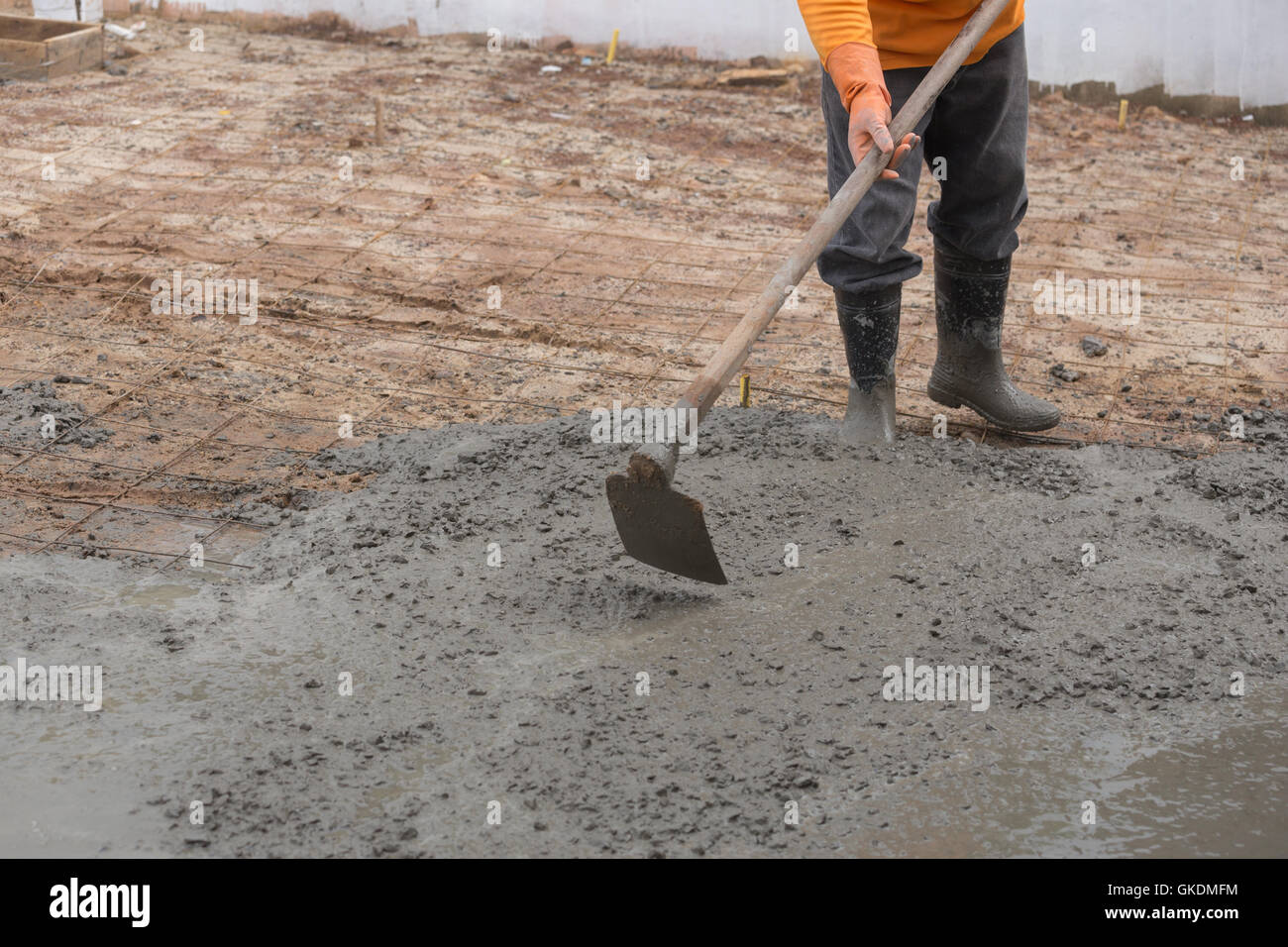 worker use hoe on a newly poured concrete floor at construction site ...