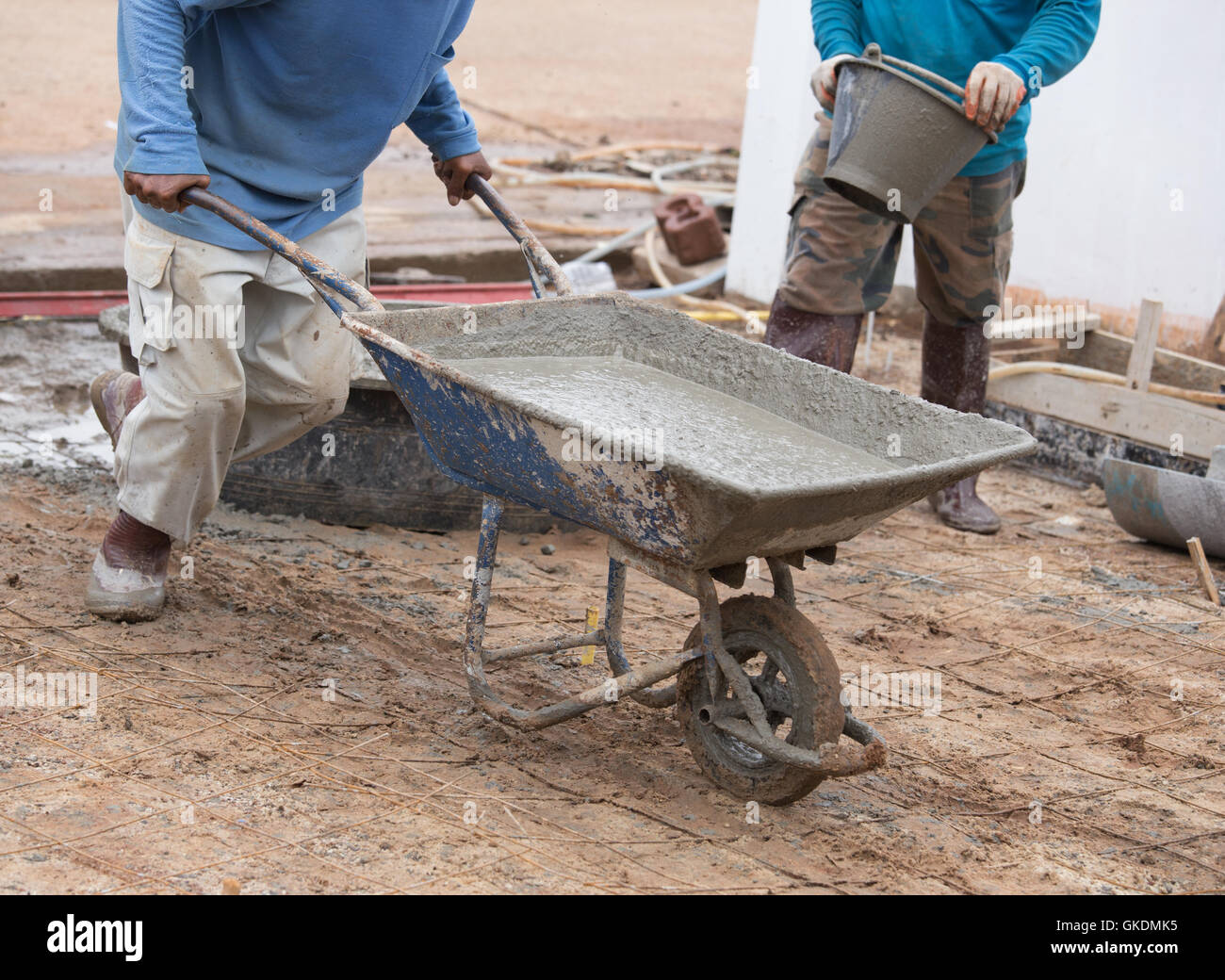 Construction worker pushing barrow with wet cement to pouring concrete ...