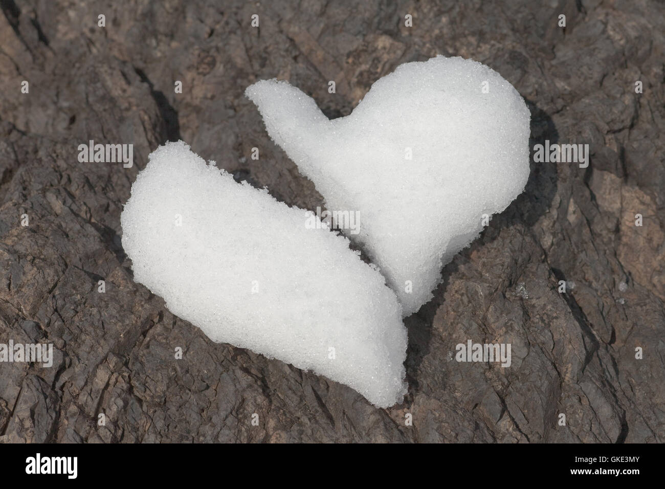 Broken heart made of snow on rock Stock Photo - Alamy