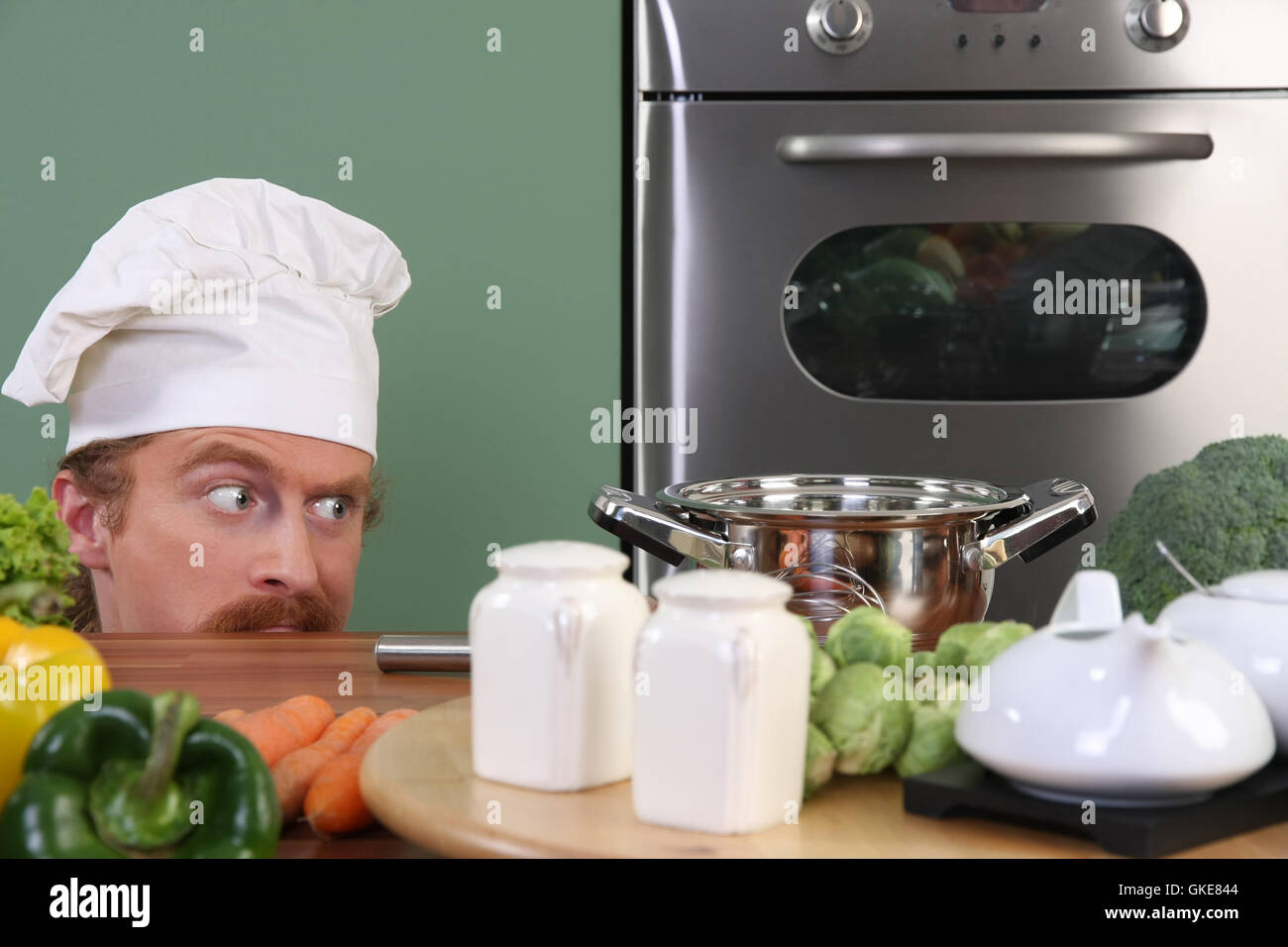 Funny young chef strange looking at pot Stock Photo - Alamy