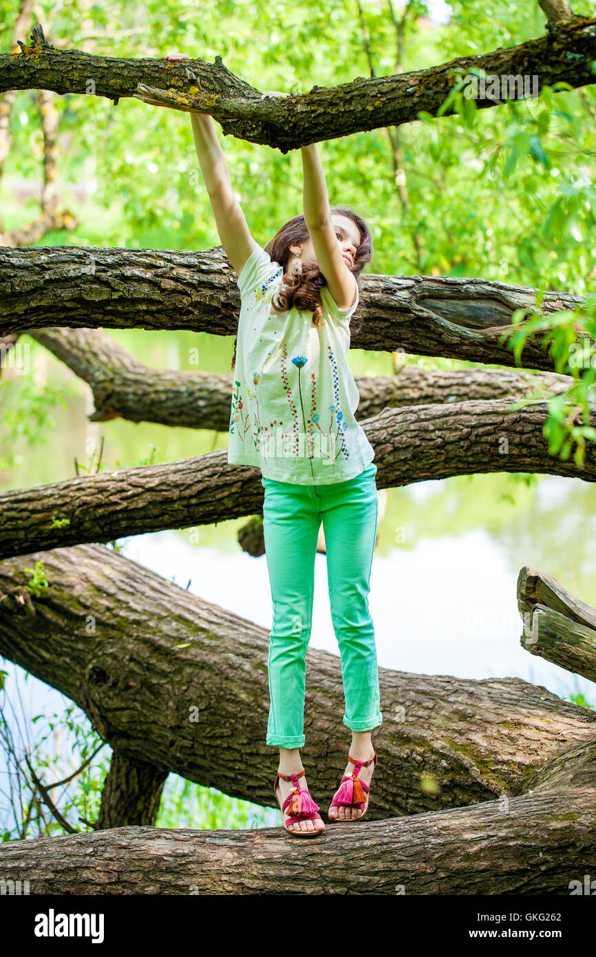 Little Girl on tree trunk on the background of summer park Stock Photo ...