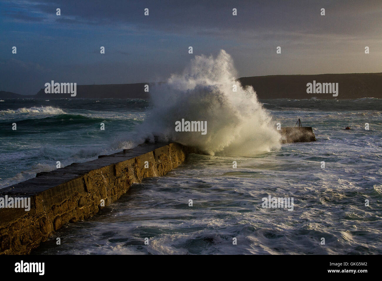 Large waves crash over the pier at Sennen during a winter storm Stock ...