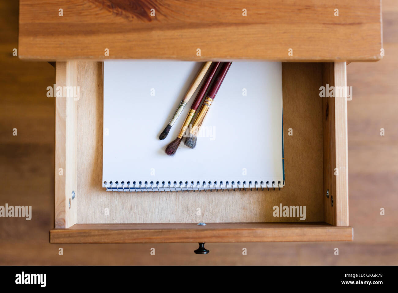top view of painting brushes on drawing album in open drawer of ...