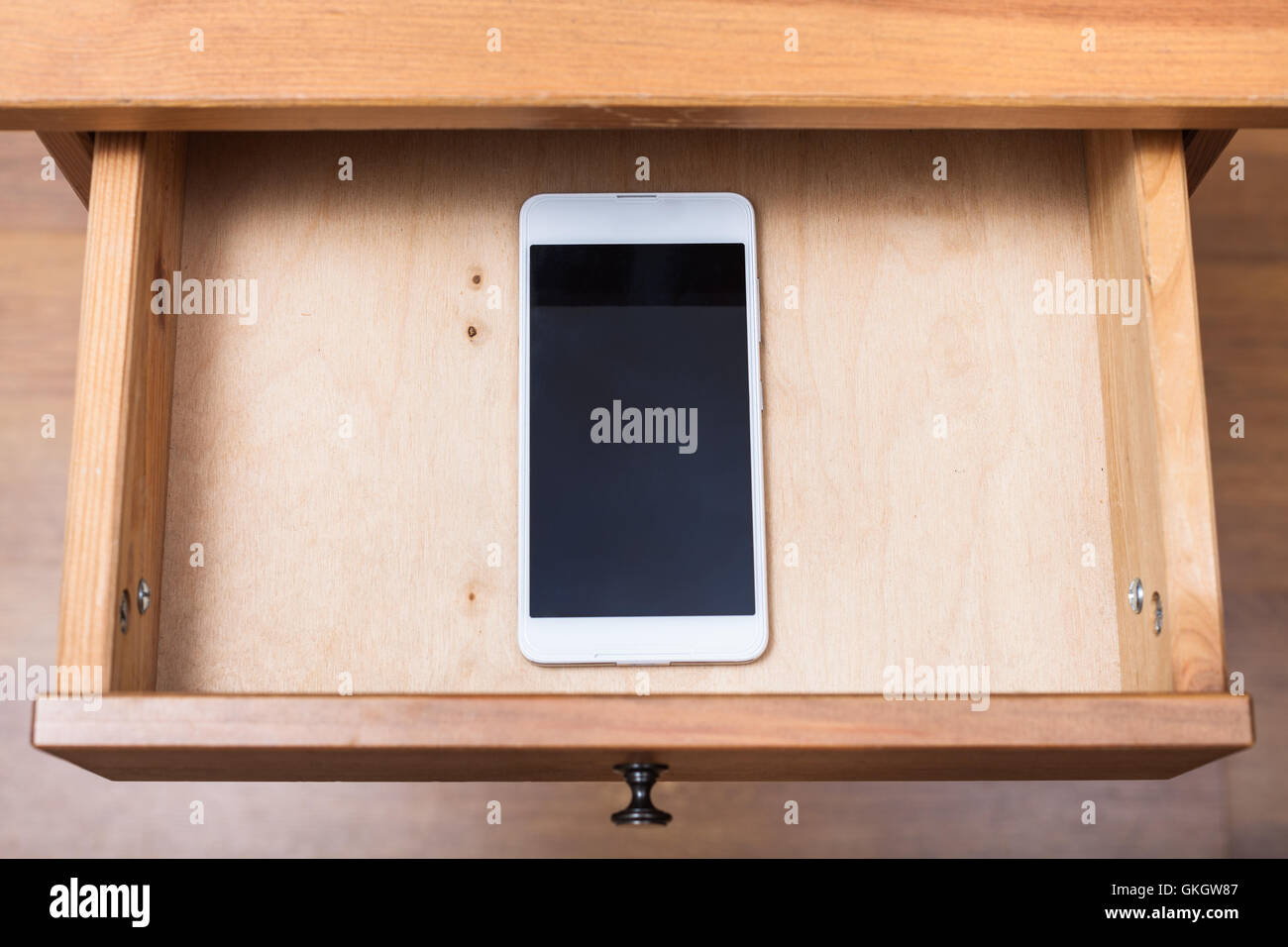 above view of mobile phone in open drawer of nightstand Stock Photo - Alamy