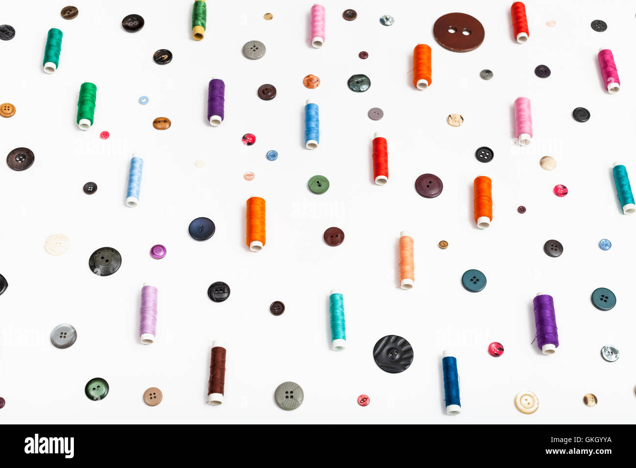 side view of spools of thread and various buttons on white background ...