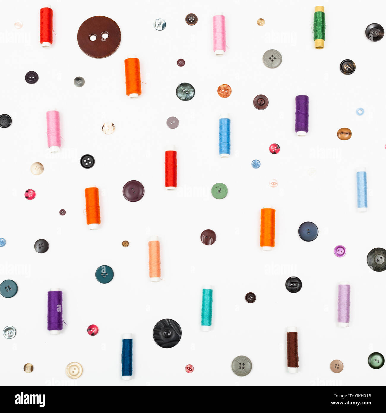 many spools of sewing thread and various buttons on square white ...