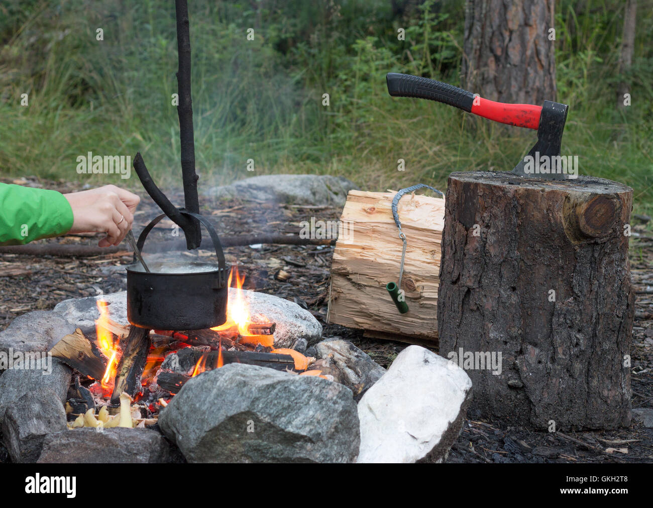 girl prepares in a cauldron on the fire, near the ax in log Stock Photo ...