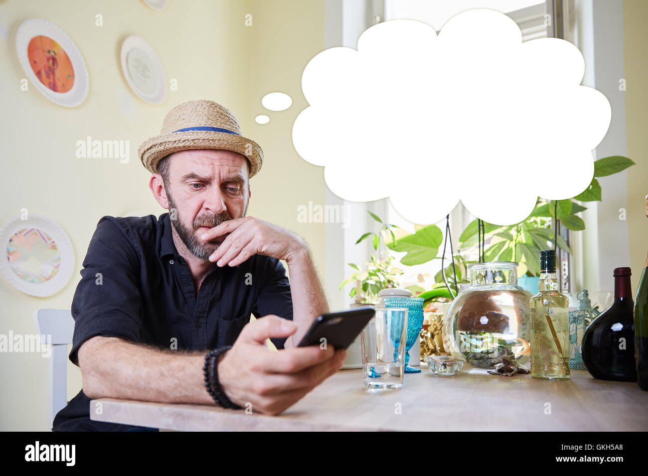 Man thinking with a thought bubble over his head sitting in a kitchen ...