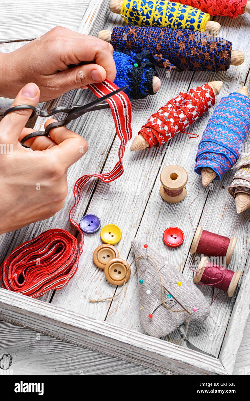 hands of tailor sewing accessories on background thread and buttons ...