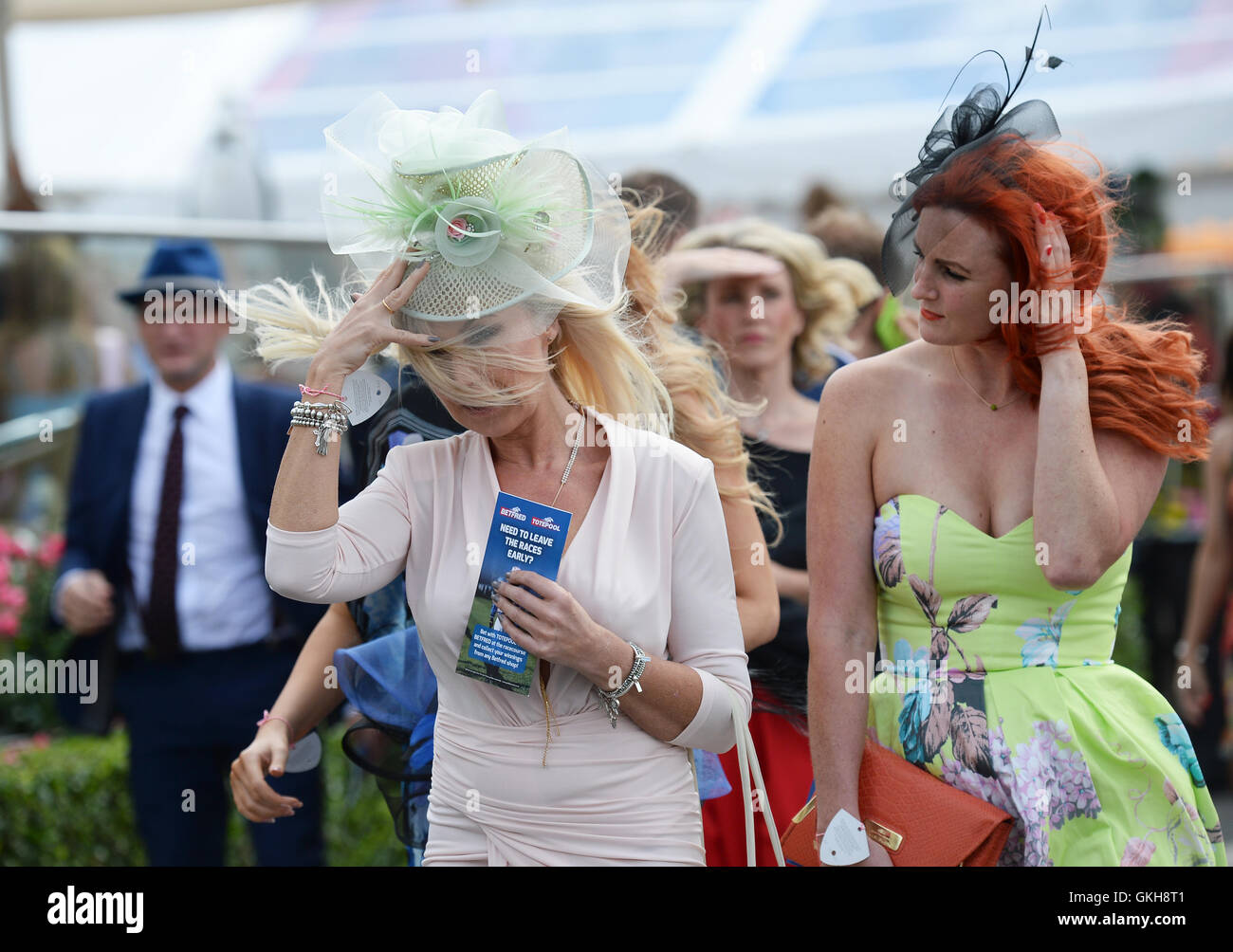 Racegoers hold on to their hats in the strong wind during day four of ...