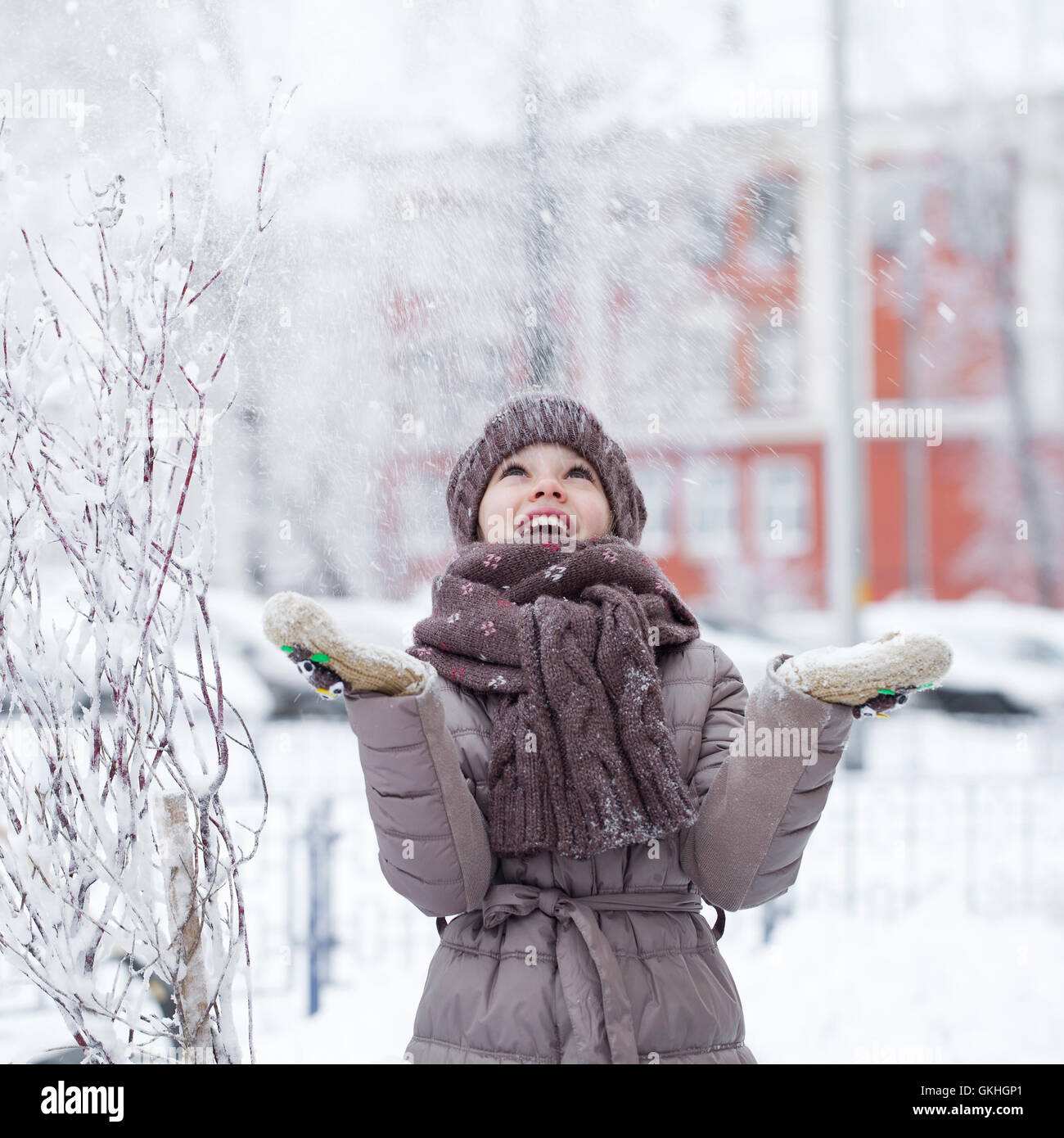 Snowfall, portrait of a happy little girl on the background of a winter ...
