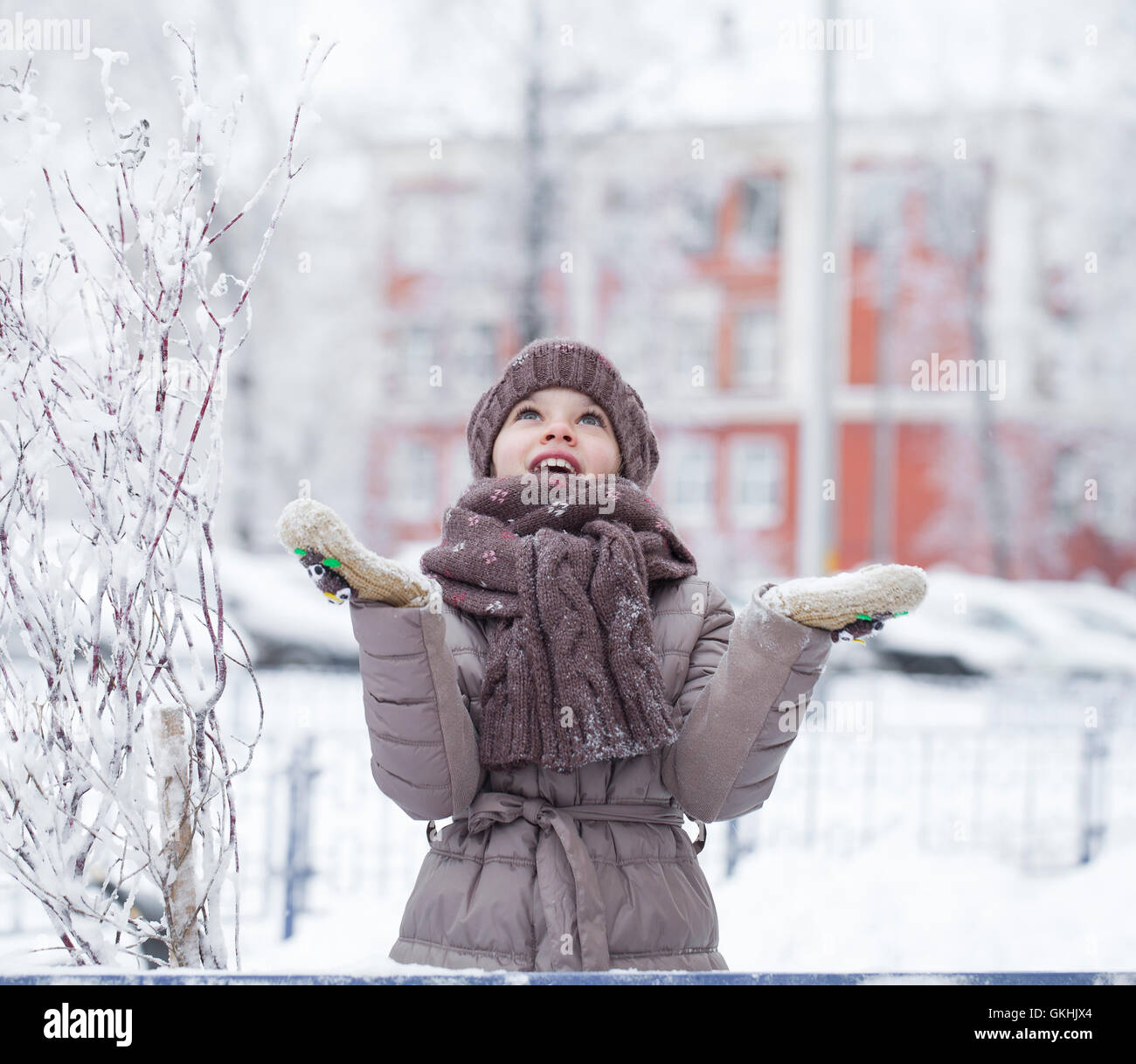 Snowfall, portrait of a happy little girl on the background of a winter ...